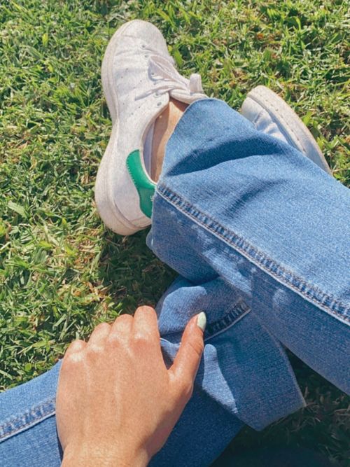 Close-up von einer Jeans und weißen Stan Smith Sneaker.