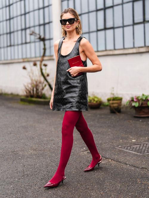 Xenia Adonts trägt ein Lederkleid mit roten Strümpfen auf der Milan Fashion Week.