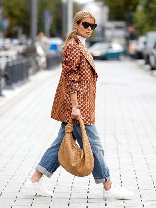 Gitta Banko in einem rostfarbenen Gucci-Blazer zu einer Boyfriend Jeans und einer gelben Bottega Veneta Tasche.