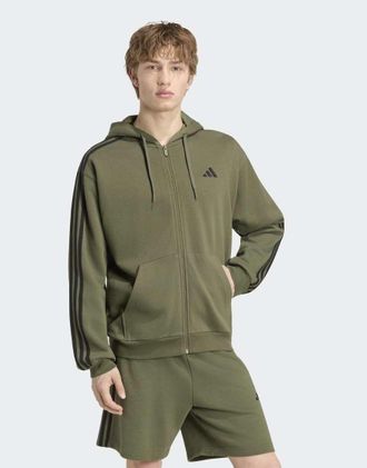 adidas Essentials - Kapuzenjacke aus French Terry in Olive Four / Schwarz mit den 3 Streifen und durchgehendem Rei&szlig;verschluss-Gr&uuml;n