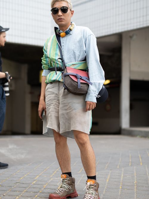 Bryanboy trägt ein leichtes Hemd, mit Statementkette, Umhängetasche, Bermudas und Wanderschuhe auf der Paris Fashion Week.