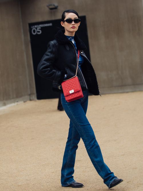 Das koreanische Model Hyun Ji Shin trägt eine schwarze Lederjacke, blue Jeans, High Heels und eine rote Crossbody Tasche auf der Paris Fashion Week.