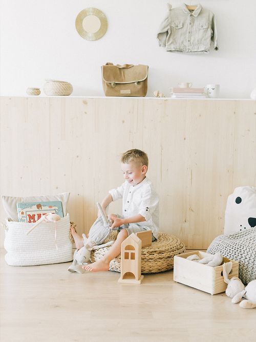 Junge sitzt auf einem Rattanpouf und spielt mit einem Stofftier.