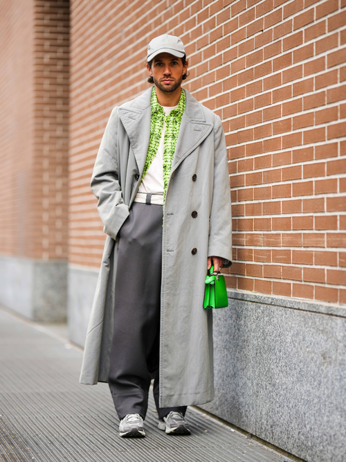JS Roques trägt einen grauen Trenchcoat, darunter einer Tweedjacke mit weißem T-Shirt und grauer Hose mit Capy auf der Milan Fashion Week.