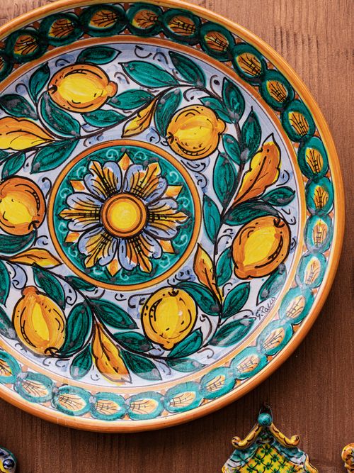Ein bunt-bemalter Teller mit Zitronen und Blätter