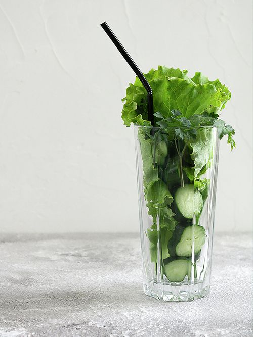 Glas gefüllt mit grünem Gemüse und einem Strohhalm.