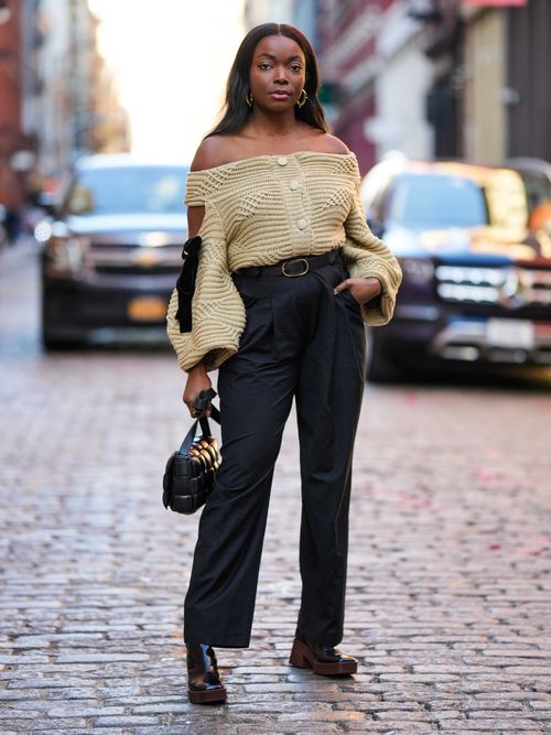 Street Style Look von der New York Fashion Week, wo ein Gast ein schulterfreies Strickoberteil mit schwarzer Hose trägt.