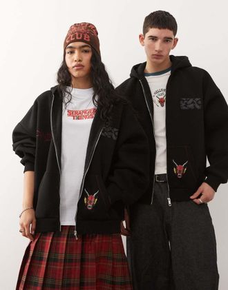 Reclaimed Vintage x Stranger Things - Sweat à capuche unisexe coupe carrée en tissu épais à écussons - Noir