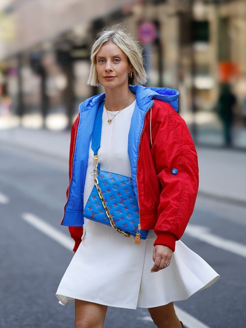 Lisa Hahnbueck in eiem weißen Kleid zu einer rot-blauen Bomberjacke und einer blauen Tasche von Louis Vuitton