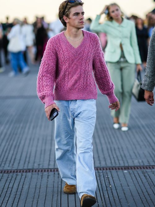 Street Style Look von der Copenhagen Fashion Week, wo ein Gast einen rosa Pulli mit V-Ausschnitt, Jeans und Birkenstock trägt.