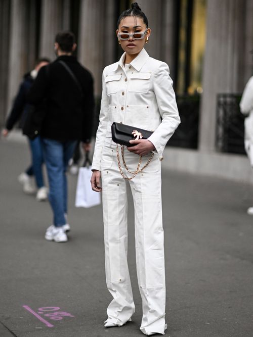 Jaime Xie trägt einen all over Denim Look in Weiß mit Sonnenbrille, schwarzer Tasche und weißen High Heels auf der Paris Fashion Week.