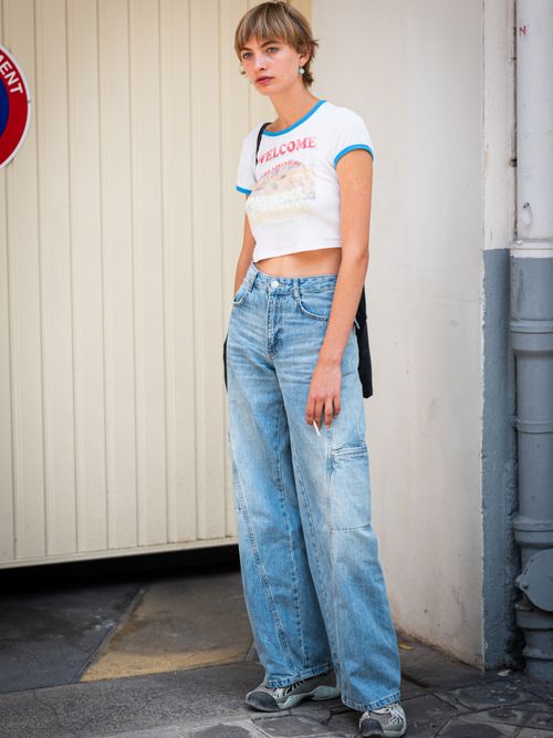 Street Style Look von Paris, wo ein Model ein Crop-T-Shirt und Baggy Pants mit Sneakers trägt.