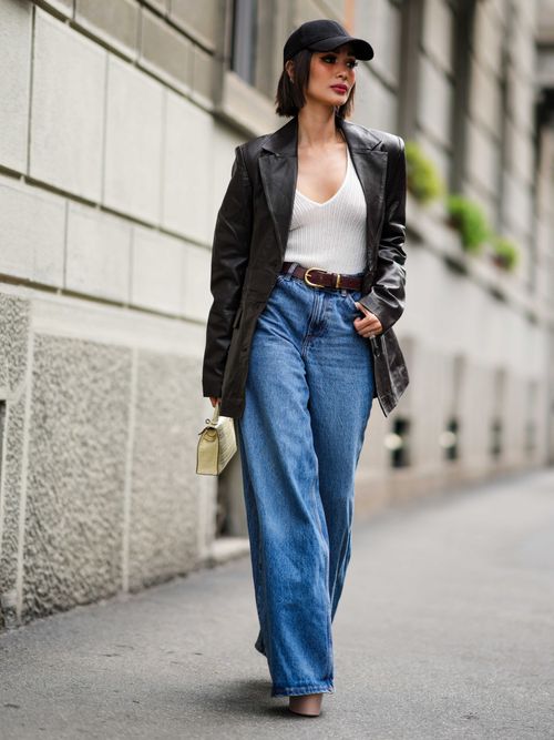 Heart Evangelista trägt einen schwarzen Lederblazer, weißes Tanktop, Baggy-Jeans mit Gürtel, Capy und Plateauschuhe auf der Milan Fashion Week.