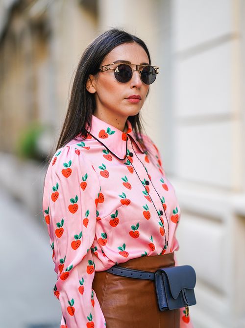 Gabriella Berdugo trägt eine Bluse mit Erdbeer-Print zu einem edlen Lederrock 