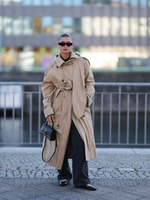 Sophia Geiss trägt einen Trenchcoat, Jeans mit Ballerinas in Berlin.