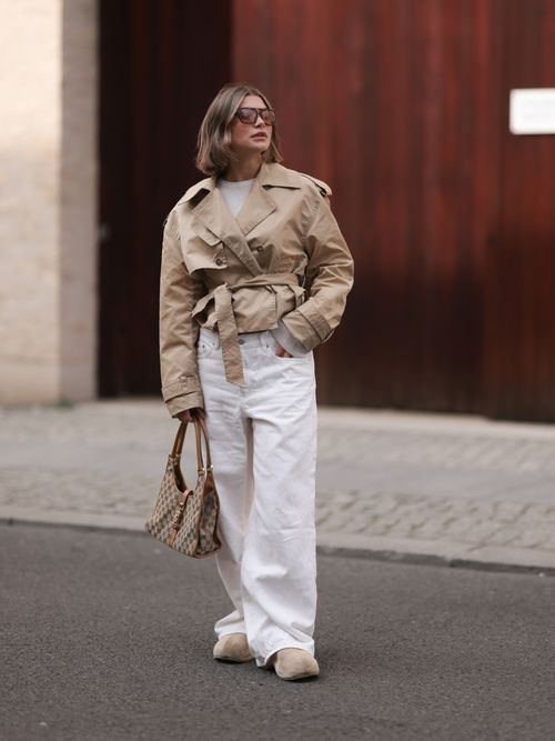 Sophia Geiss trägt einen kurzen Trenchcoat, weiße Denim, Gucci Tasche und Sneaker in München.
