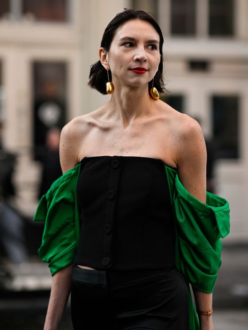 Ana Tess trägt ein schwarzes schulterfreies Top mit grünen Ärmeln und einer schwarzen Hose auf der New York Fashion Week.