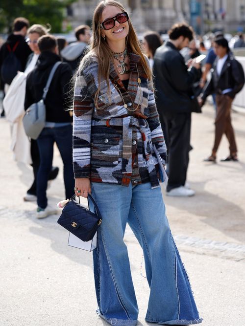 Carlotta Oddi trägt eine bunte Strickjacke mit weiter Jeanshose, Sonnenbrille und Chaneltasche auf der Paris Fashion Week.