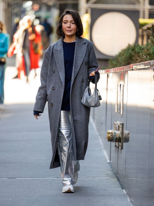 Street Style Look von der New York Fashion Week, wo ein Gast eine Silber-Hose mit grauem Mantel und schwarzem T-Shirt trägt.