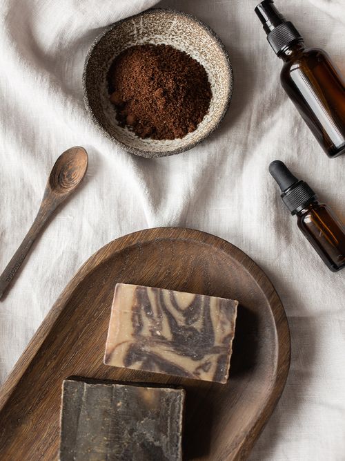 Ovales Holztablett mit Seife und eine Schüssel mit Kaffeesatz.