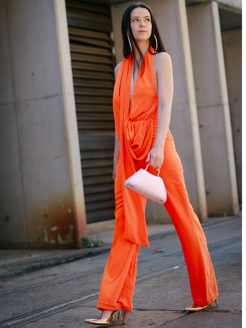 Alice Margot Christie trägt einen orangefarbenen Overall mit goldenen High Heels auf der Austrialian Fashion Week.